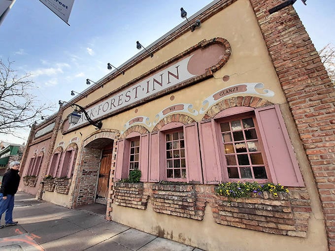 The charming facade of Black Forest Inn beckons with its distinctive pink shutters and rustic brick exterior &ndash; a Bavarian postcard in Minneapolis.