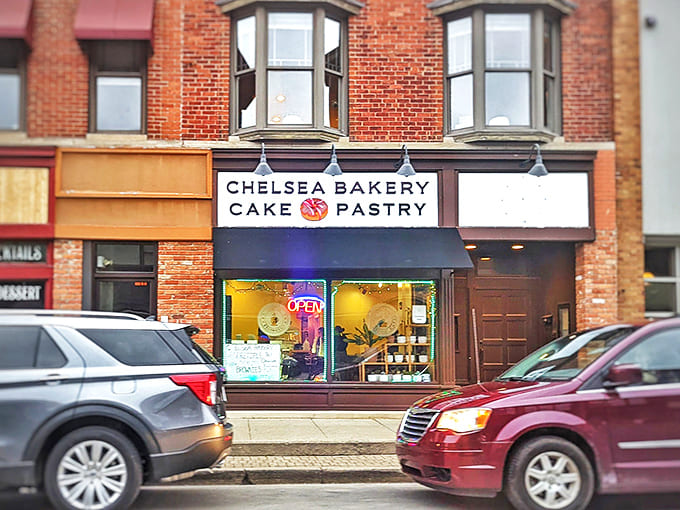 Chelsea Bakery's charming storefront beckons with its classic sign and warm glow, promising sweet treasures within the brick building.