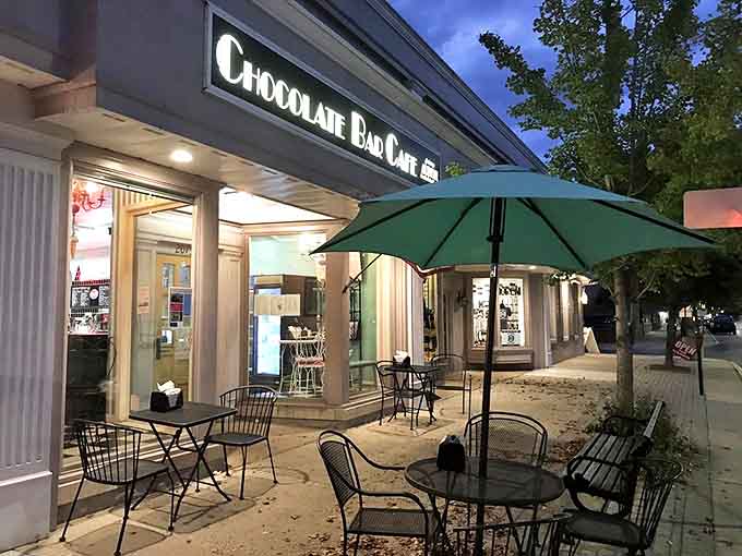 The Chocolate Bar Cafe's inviting storefront glows with promise as dusk settles over Mack Avenue, beckoning sweet-toothed travelers with its nostalgic charm.