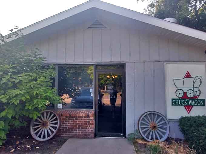 The unassuming exterior of Chuck Wagon Pizza, complete with iconic wagon wheels, promises frontier-sized portions inside this Ludington landmark.
