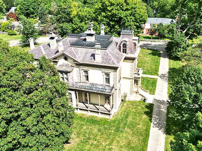 An aerial view of the David Davis Mansion showcases its impressive Second Empire architecture nestled among mature trees like a Victorian jewel box.