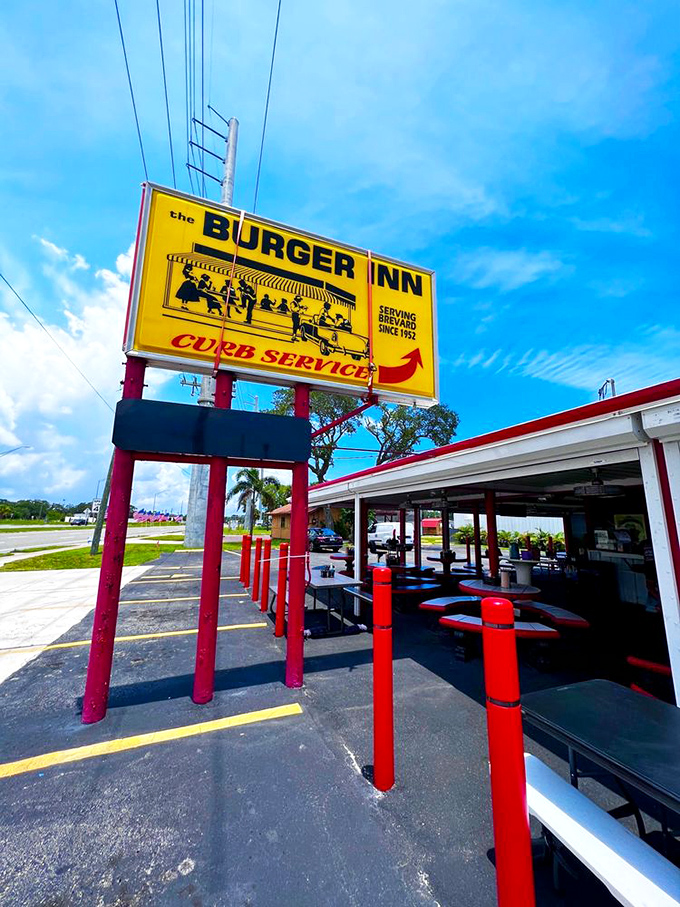 The iconic yellow Burger Inn sign stands proudly against the Florida sky, promising curb service and timeless flavors since 1952.