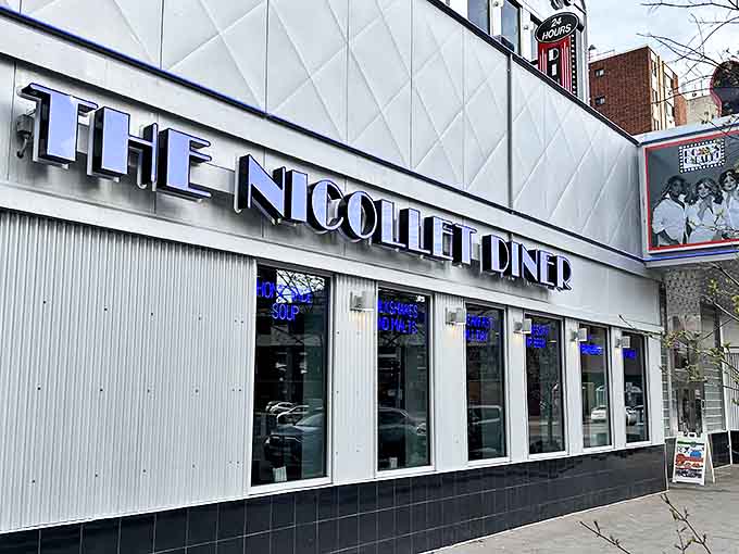 The gleaming white exterior of The Nicollet Diner stands as a 24-hour beacon for hungry souls, its bold blue signage promising delicious salvation at any hour.