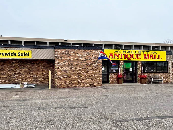 The unassuming brick exterior of Hallett Antique Mall belies the time-traveling adventure waiting inside. Yellow signage promises treasures beyond the ordinary.
