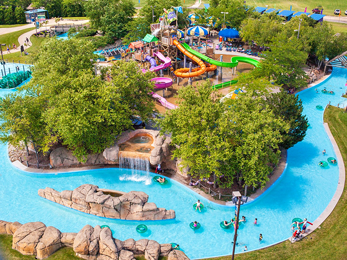 Aerial view paradise: Colorful slides and a winding lazy river create a water wonderland nestled among lush greenery.