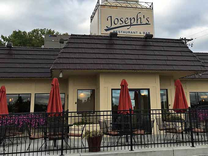 Joseph's Restaurant welcomes hungry travelers with its cream-colored exterior, distinctive brown roof, and those eye-catching orange patio umbrellas that practically scream "good times ahead!"