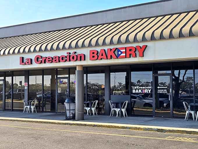 The vibrant storefront of La Creaci&oacute;n Bakery beckons with its bold red lettering and Puerto Rican flag, a tropical oasis in suburban Tampa.