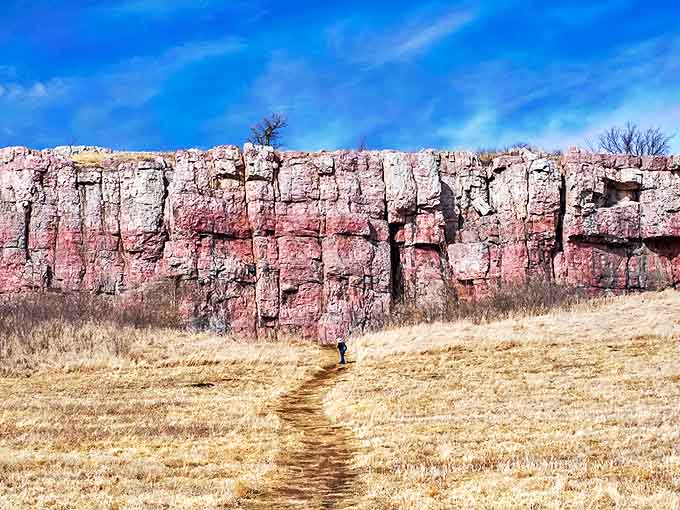 The majestic pink quartzite cliffs of Blue Mounds stand like ancient sentinels, their billion-year-old faces catching the Minnesota sunlight with timeless grace.
