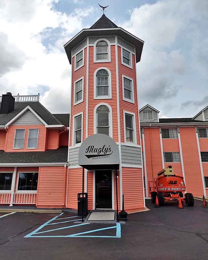 Standing tall like a salmon-colored lighthouse, Muglys' distinctive tower beckons hungry travelers with whimsical charm and architectural personality.