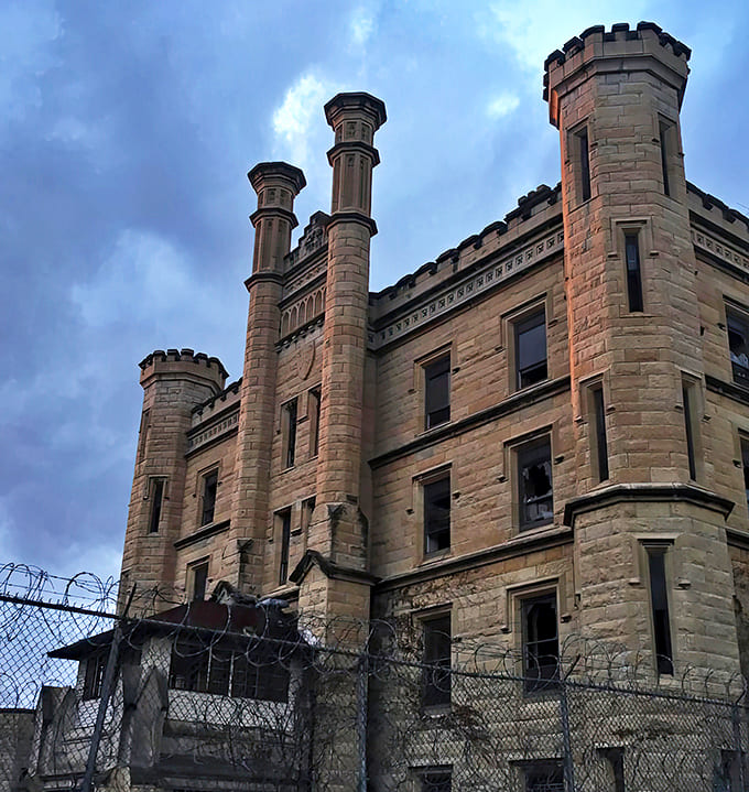 The imposing limestone facade of Old Joliet Prison stands like a medieval castle, its turrets and battlements silhouetted against the Midwestern sky.