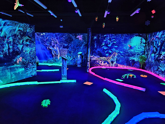 The vibrant entrance to Rainforest Black Light Golf & Arcade beckons visitors with its electric green and purple signage, promising a glowing adventure within.