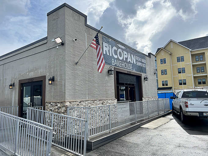 Exterior: A modest gray building with an American flag proudly waving, Ricopan Bakehouse's unassuming exterior hides the Colombian culinary treasures within.