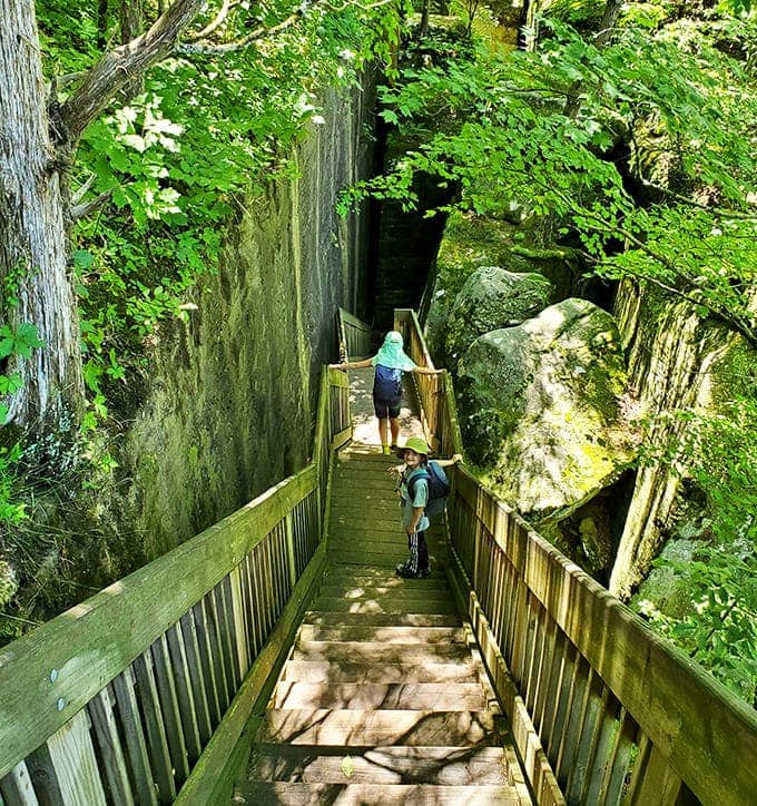 Those wooden steps descending between ancient rock walls look like the entrance to a secret world, and honestly, that's pretty much what they are.