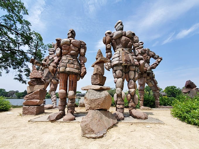 Imposing stone warriors stand guard by the Rock River, their muscular forms crafted entirely from carefully stacked rocks.