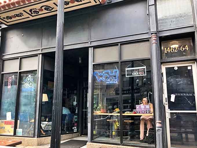 The unassuming storefront of Wormhole Coffee hides a time-traveling adventure within. Look for the blue neon "WH" sign marking the spot.