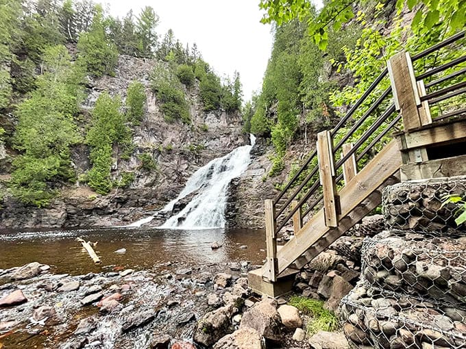 Caribou Falls cascades dramatically between rugged cliffs, creating nature's perfect soundtrack. The wooden staircase invites adventure seekers closer to the misty spectacle.