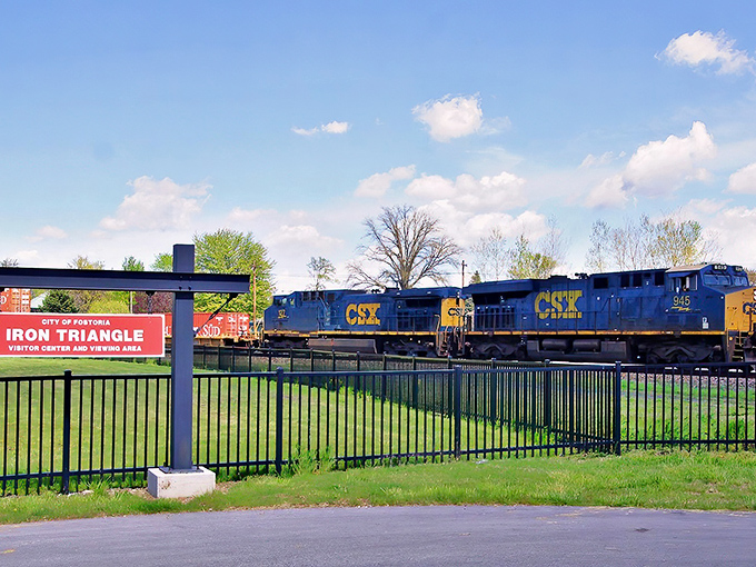 The iconic Iron Triangle sign welcomes visitors to Fostoria's train-watching paradise, where steel giants rule the rails.