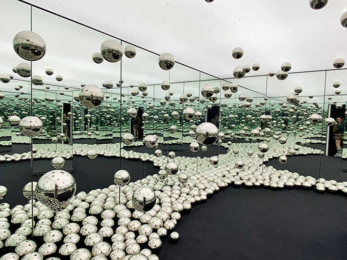 Step into the WNDR Museum's mirror ball infinity room, where reality multiplies endlessly and your sense of space dissolves into silver spheres.