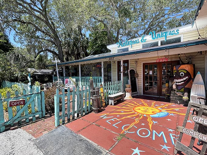 The whimsical entrance to Antiques & Uniques beckons with its turquoise picket fence and vibrant sun mosaic &ndash; a portal to treasures beyond.