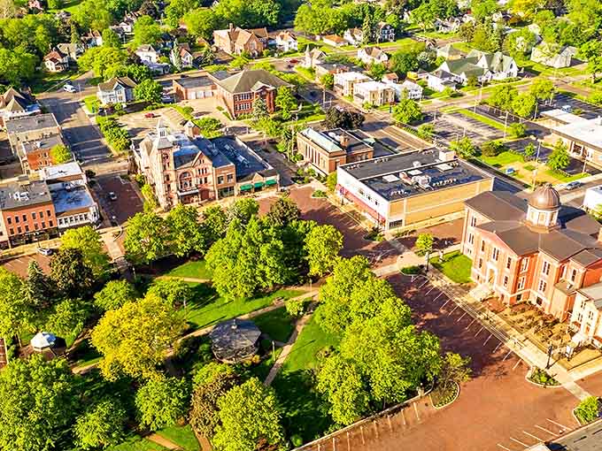 Aerial view of Woodstock, Illinois reveals a perfect small-town tapestry where historic architecture and lush greenery create a scene worthy of a movie set.