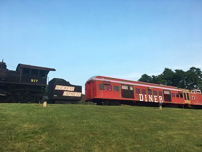 The iconic red train car of Buckeye Express Diner sits proudly alongside its black locomotive companion, a scarlet beacon for hungry travelers.