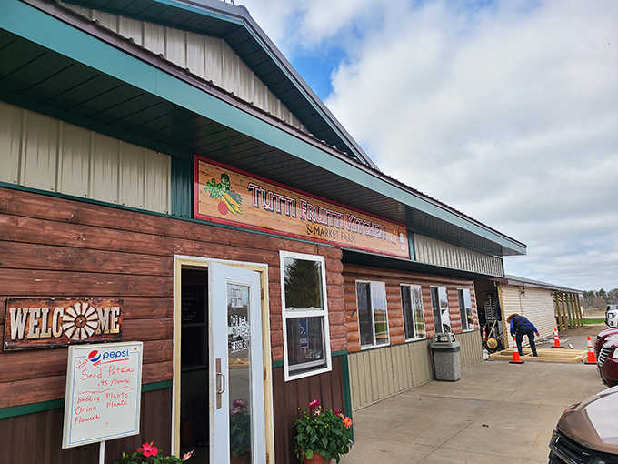 Rustic charm meets culinary magic at Tutti Fruitti Kitchen & Market Farm, where the log cabin exterior hints at the homestyle treasures waiting inside.