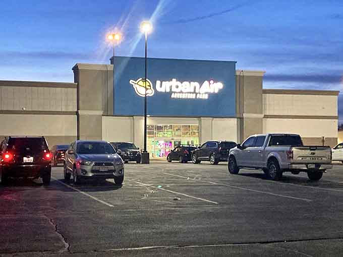 The Urban Air Adventure Park exterior glows like a beacon of fun against the twilight sky, promising gravity-defying adventures within its walls.