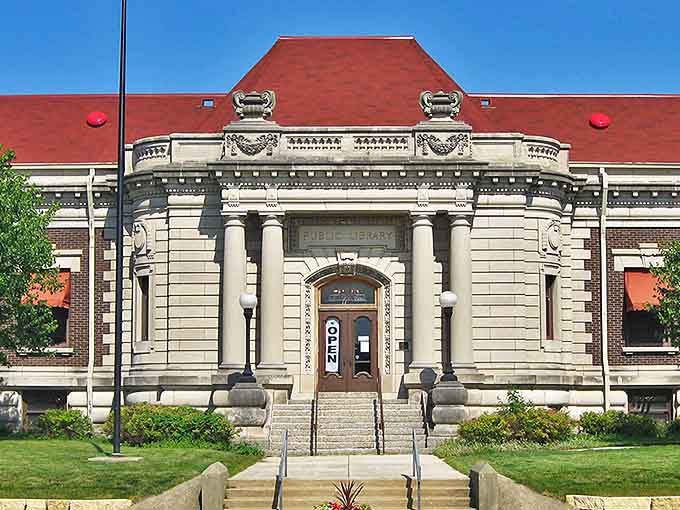 That striking red tile roof and classical architecture make this former library building look like it belongs on a postcard from a more elegant era.