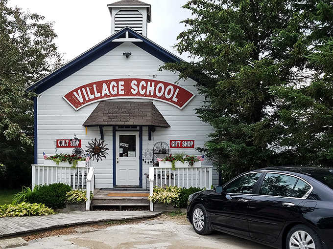 The charming white schoolhouse with its iconic red "VILLAGE SCHOOL" sign welcomes visitors to a world where craftsmanship and tradition still reign supreme.