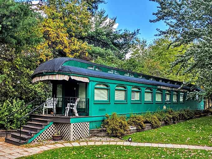 The emerald-green passenger car gleams in Minnesota sunshine, inviting travelers to experience railroad luxury without ever leaving the station.