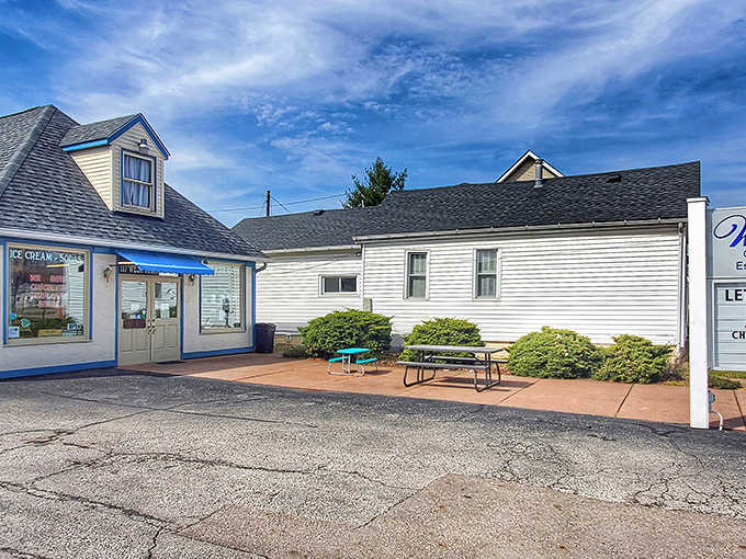 The charming blue-trimmed exterior of Wittich's Candy Shop stands as a sweet beacon in Circleville, complete with inviting picnic tables for enjoying your sugary treasures.