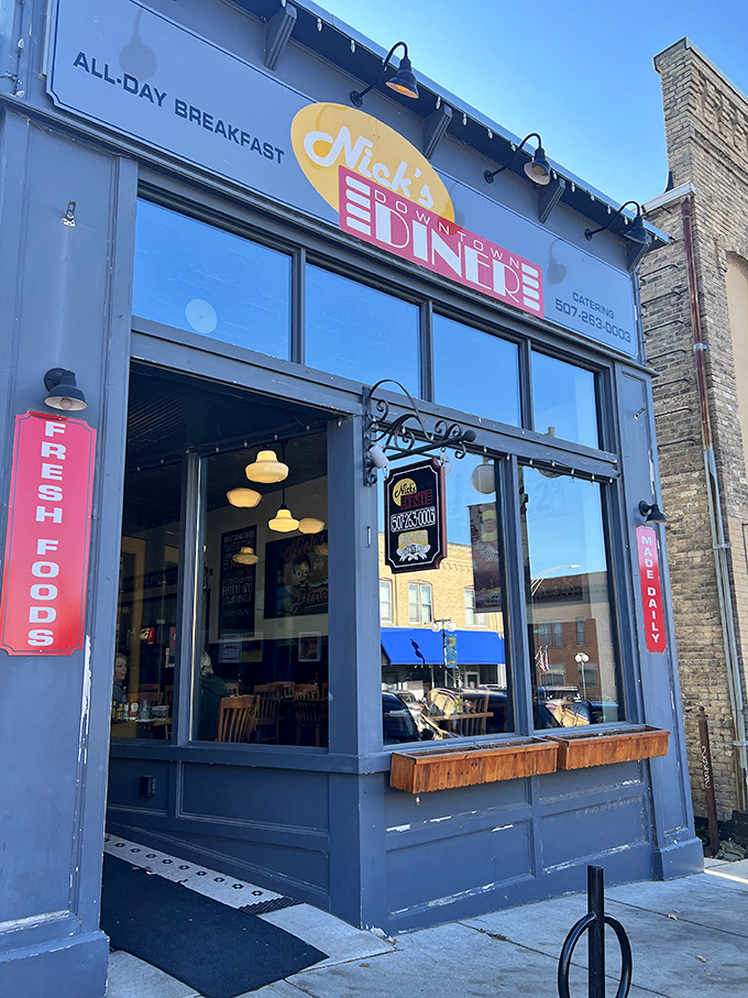 The blue storefront of Nick's Downtown Diner beckons with its cheerful yellow and pink signage, promising all-day breakfast and hometown charm.