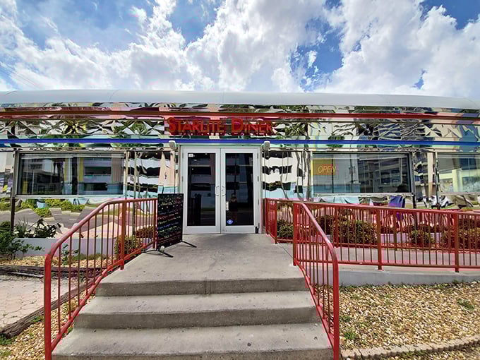 The gleaming chrome exterior of StarLite Diner beckons with retro charm, its red railings rolling out the welcome mat to time travelers and food lovers alike.