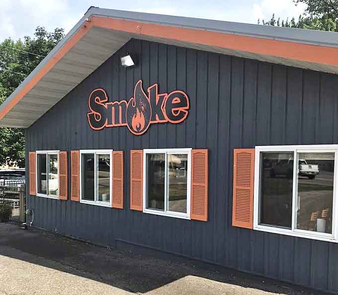 Smoke's navy blue exterior with vibrant orange signage stands as a beacon for barbecue pilgrims, promising smoky treasures within its humble walls.