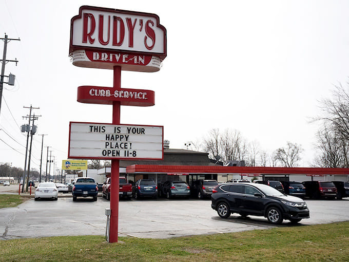 The iconic Rudy's Drive-In sign stands tall, promising "Your Happy Place" with its vintage red glow that beckons hungry travelers from miles around.