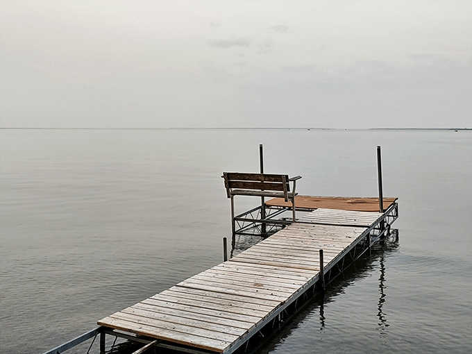 The simple wooden dock stretches toward possibility, inviting contemplation, conversation, or just watching ripples disappear into the misty horizon.
