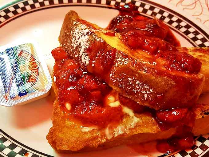 French toast fantasy: Thick-cut bread soaked in custard, griddled golden, and topped with strawberry compote &ndash; breakfast that thinks it's dessert.