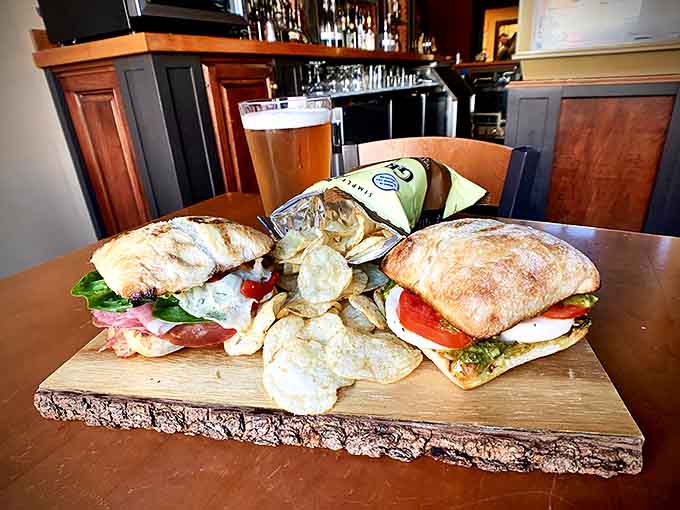 Artisanal sandwiches served on a rustic wood board with house-made chips prove the Riviera's culinary prowess extends well beyond their famous pizzas.