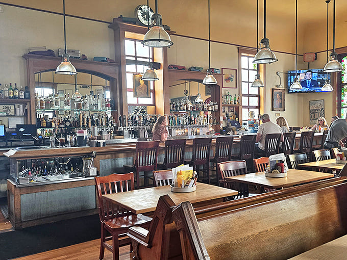 The bar stretches impressively along one wall, bottles gleaming like sacred vessels while patrons gather for libation and conversation.