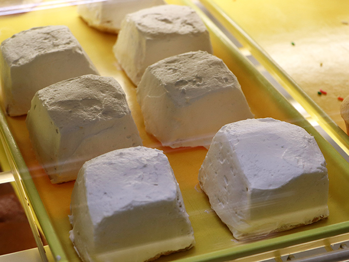 These pristine white cakes sit like little snow-capped mountains of sweetness, promising a melt-in-your-mouth experience with every bite.