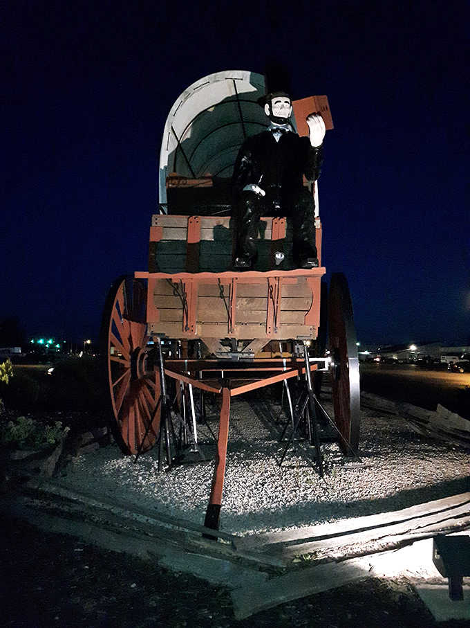 Even after sunset, the illuminated wagon continues to draw visitors, a beacon of Americana glowing in the prairie night.