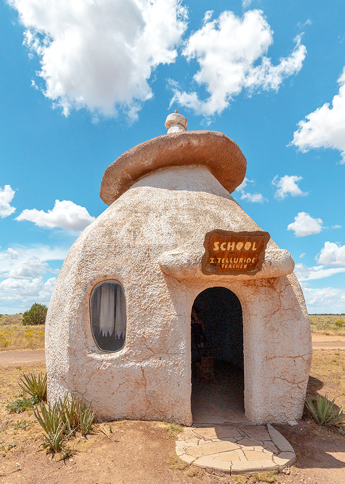 The whimsical schoolhouse stands ready for prehistoric pupils, its rounded dome and "Telluride Teacher" sign adding educational authenticity.