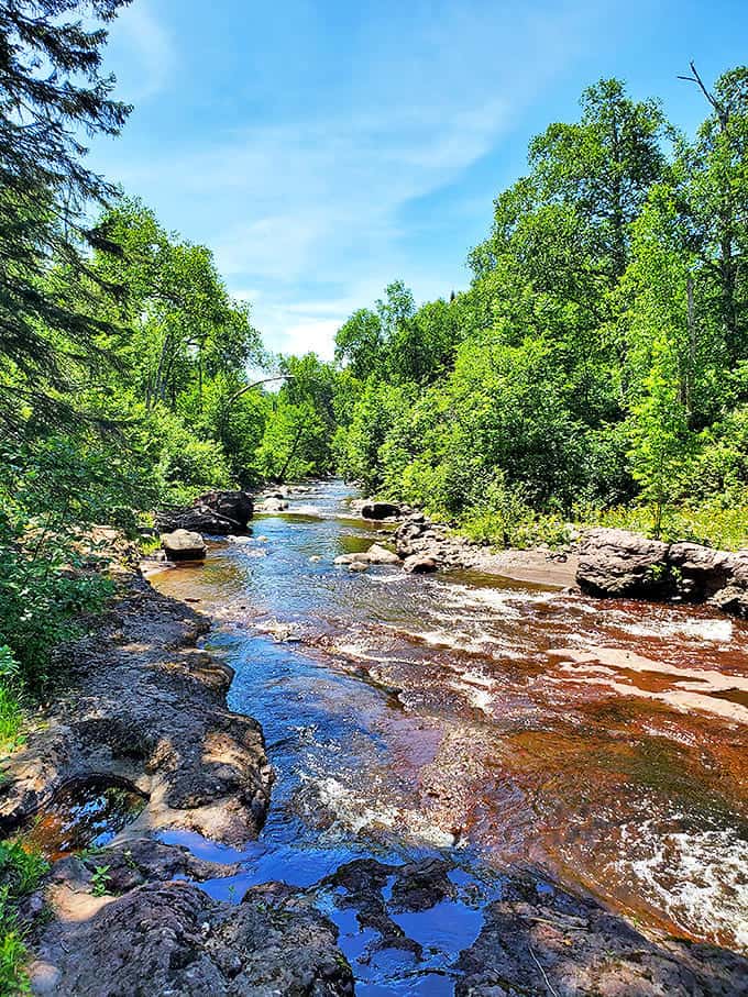 Crystal clear waters meander over colorful stones, nature's own stained glass window. The gentle current whispers stories of its journey from highlands to lake.