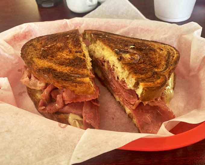 Sam's Reuben sandwich achieves the perfect balance of corned beef, sauerkraut, Swiss cheese, and Russian dressing &ndash; a deli classic done right.