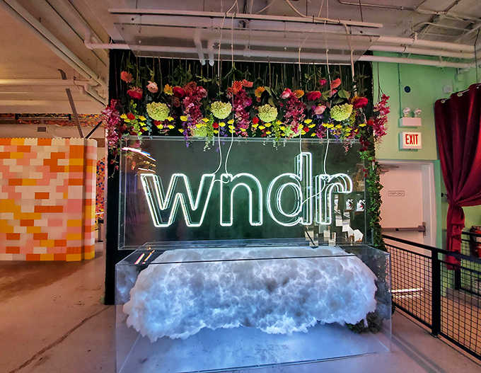 The "WNDR" sign surrounded by cascading flowers creates the perfect blend of natural beauty and neon-lit modernity.