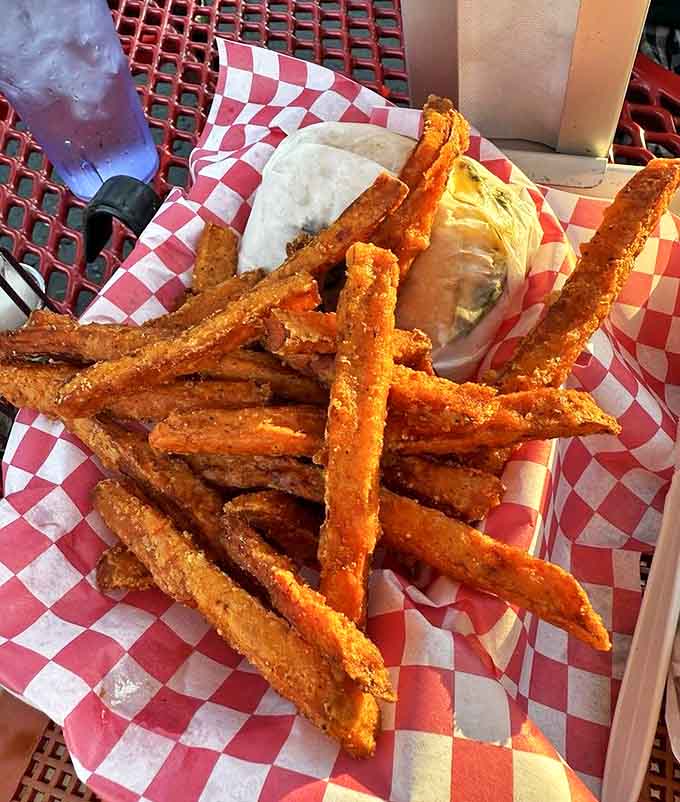 Sweet potato fries with the perfect crisp-to-tender ratio accompany a burger that requires both hands and zero regrets.
