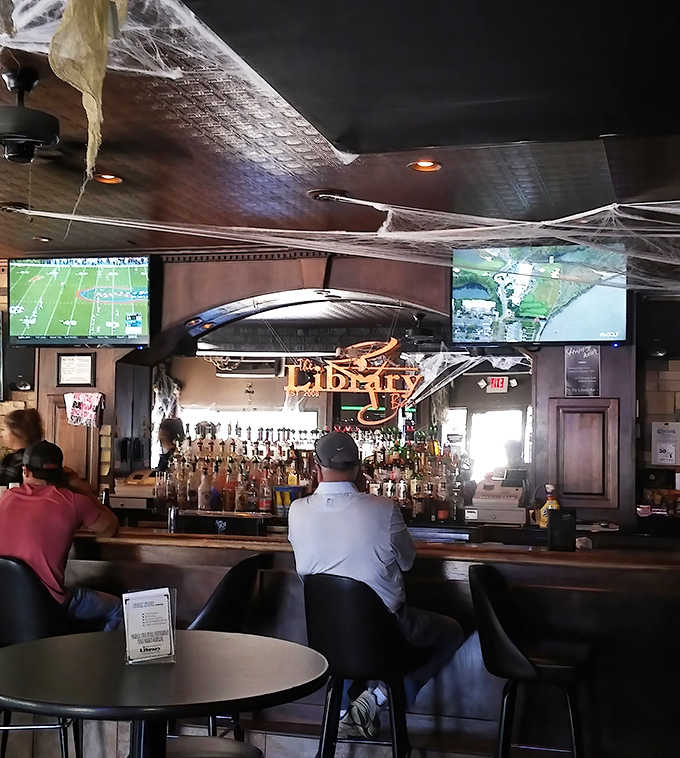 Where stories unfold in real-time &ndash; patrons gather at the bar to watch games, share tales, and create memories beneath the Library's signature sign.
