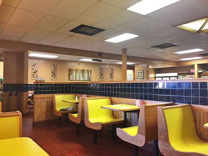 Yellow booth seating pops against earthy tones, creating spaces where strangers become friends over shared appreciation of perfectly cooked comfort food.