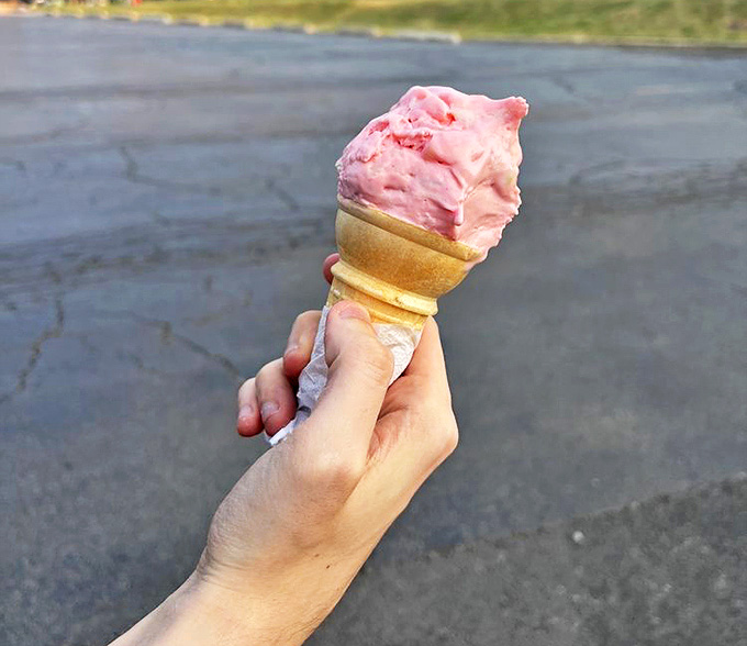 A perfectly scooped cone of pink ice cream catches the evening light, promising sweet relief from summer heat with every melting drop.