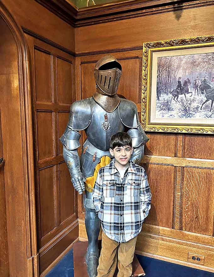 A young visitor stands beside a suit of armor, history coming alive through these tangible connections to a bygone era of knights and castles.